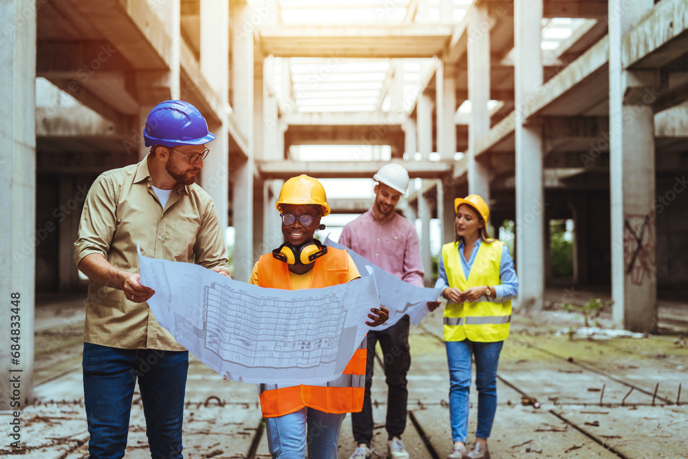 Team of construction workers discussing project details with executive ...