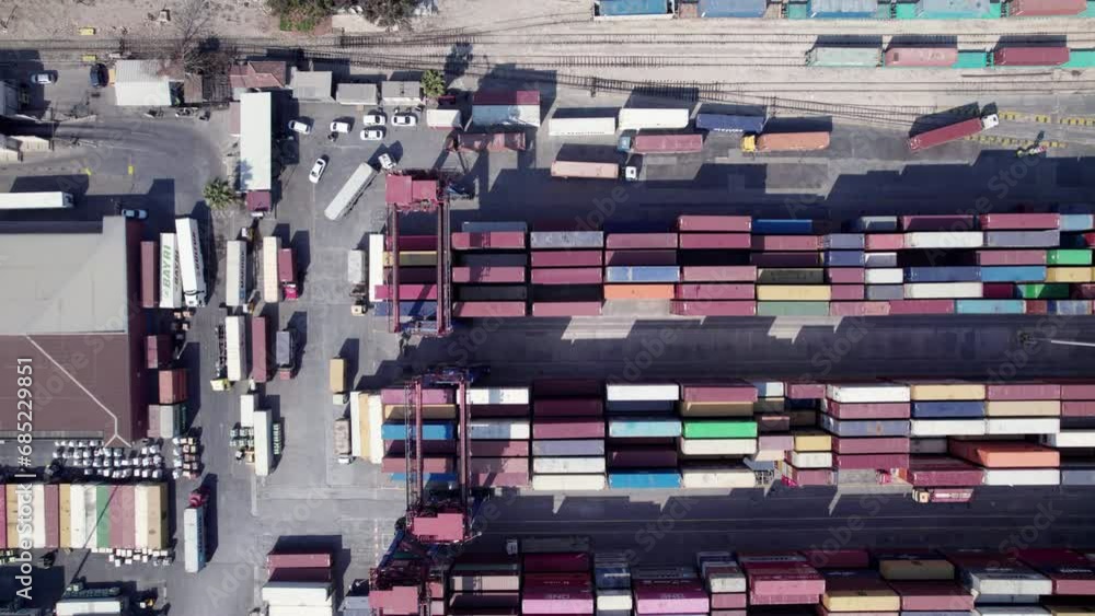 Trucks and cars driving between stacked cargo containers top down ...