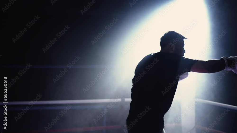 Young fighter punching the air inside boxing ring with dramatic ...