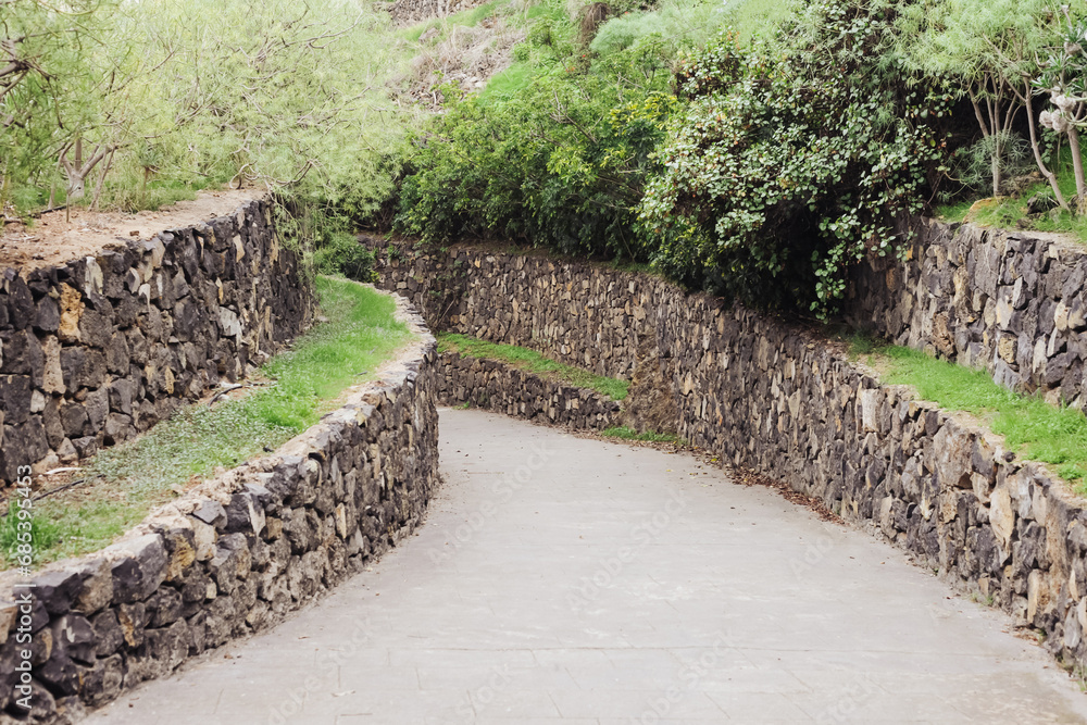 Walking path on Tenerife island. Rock solid wall among pavement. Brick ...