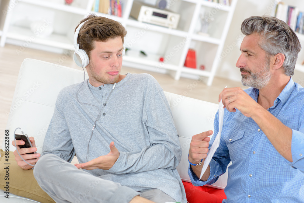 Man holding piece of paper and demanding explanation from younger man ...