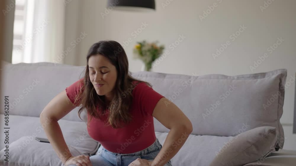 Caucasian woman standing up from a couch at home experiences sudden ...