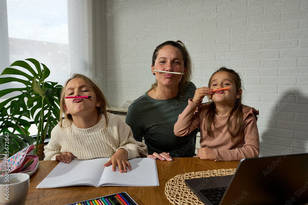 Homework fun: Mother and daughters, seated at the dining table, make ...