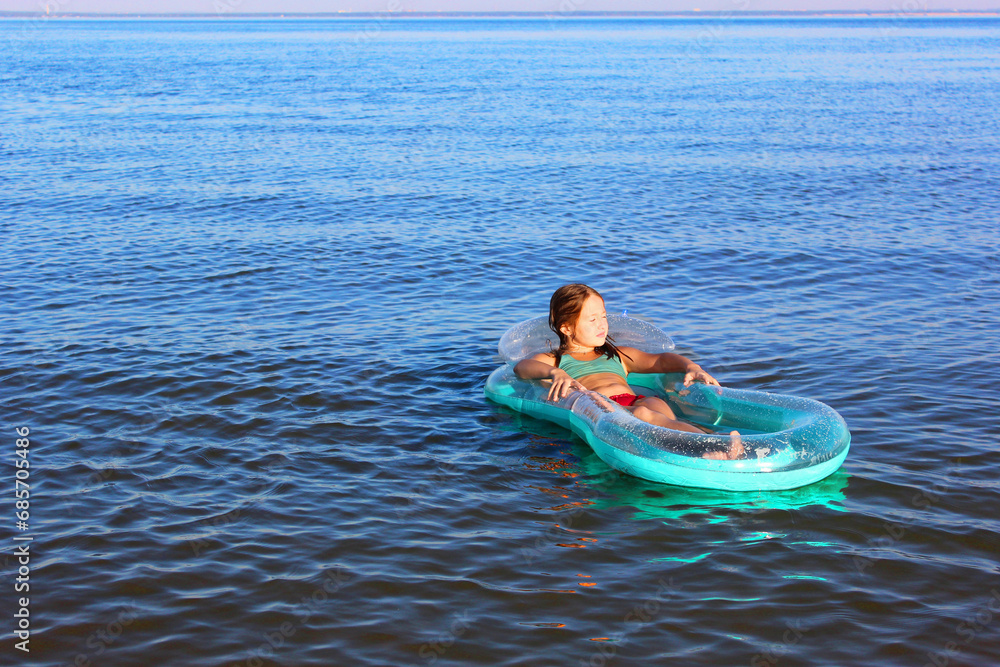 little happy girl in the sea with blond hair in a swimsuit floating in ...