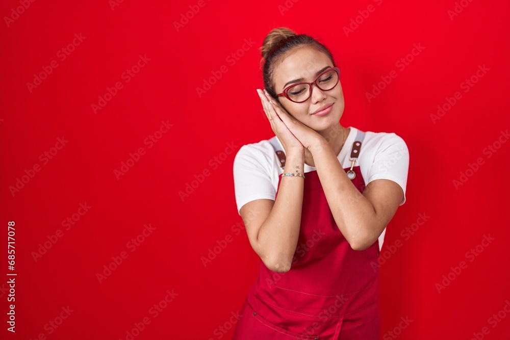 Young hispanic woman wearing waitress apron over red background ...