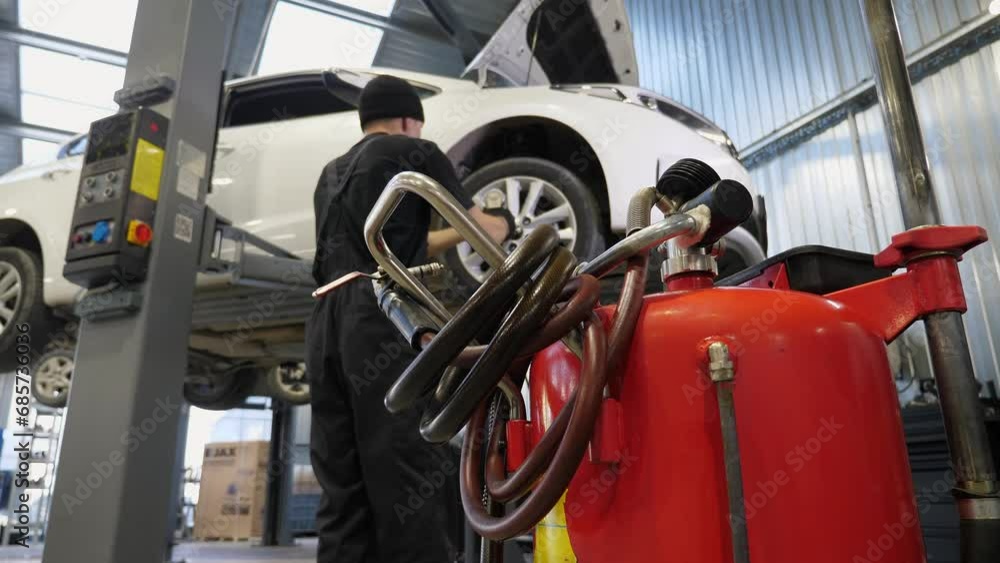 A gas cylinder with a pressure gauge stands near the car on the lift at ...