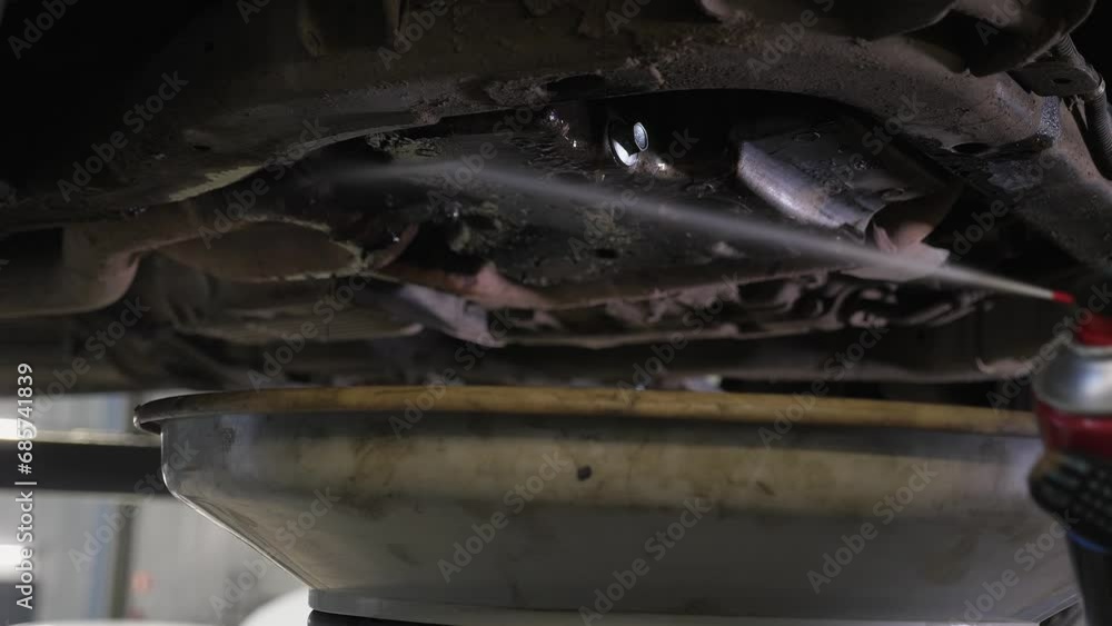Close-up of the bottom washing after oil change with a jet of water at ...