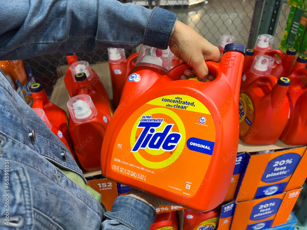 Shopper holding a Plastic container of Tide brand liquid laundry ...