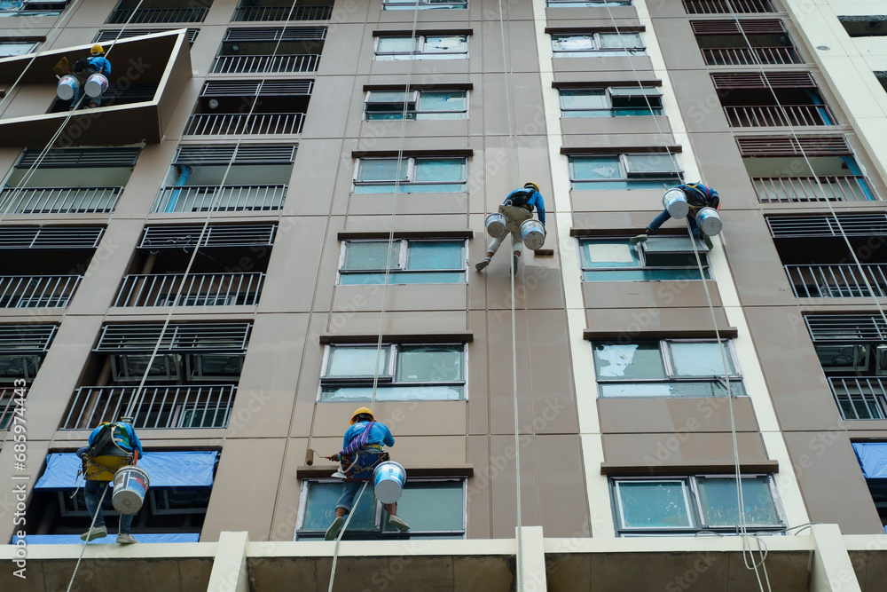 A painter is abseiling from a high-rise building. A painter using sling ...
