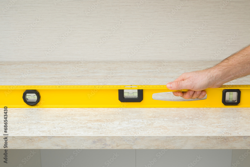 Young adult man hand using yellow spirit level and measuring horizontal ...