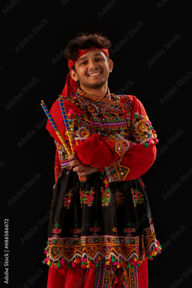 Portrait of Gujarati man in traditional outfit standing with Dandiya ...