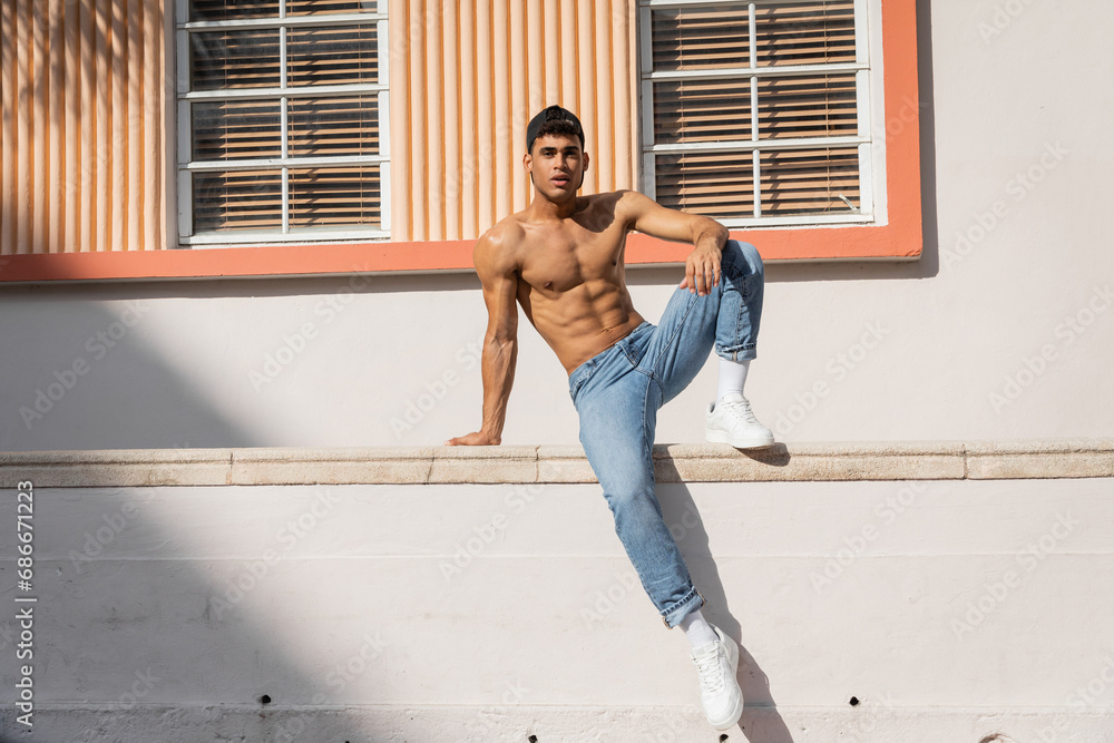 cuban man with muscular body posing in baseball cap and jeans on street ...