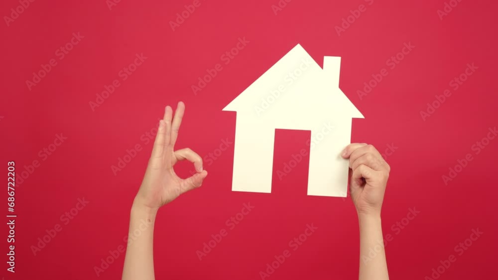 Close up of woman hands holding white house model and makes okay ...