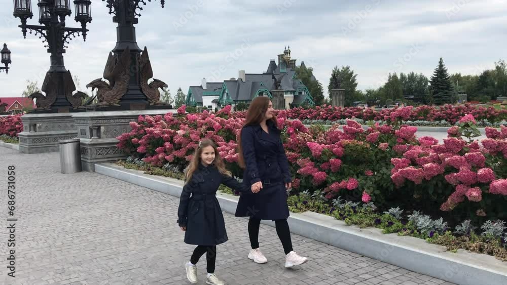 Mom and daughter walk in the park with hydrangeas. A beautiful woman ...