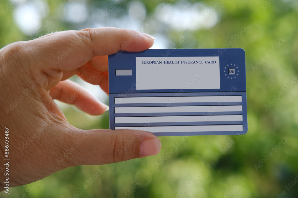 German health insurance card in female hand on natural green background ...