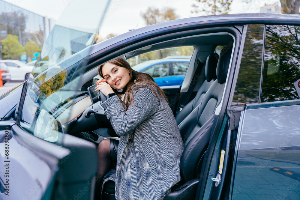 Attractive young woman enjoying new car, sits at driver seat in modern ...