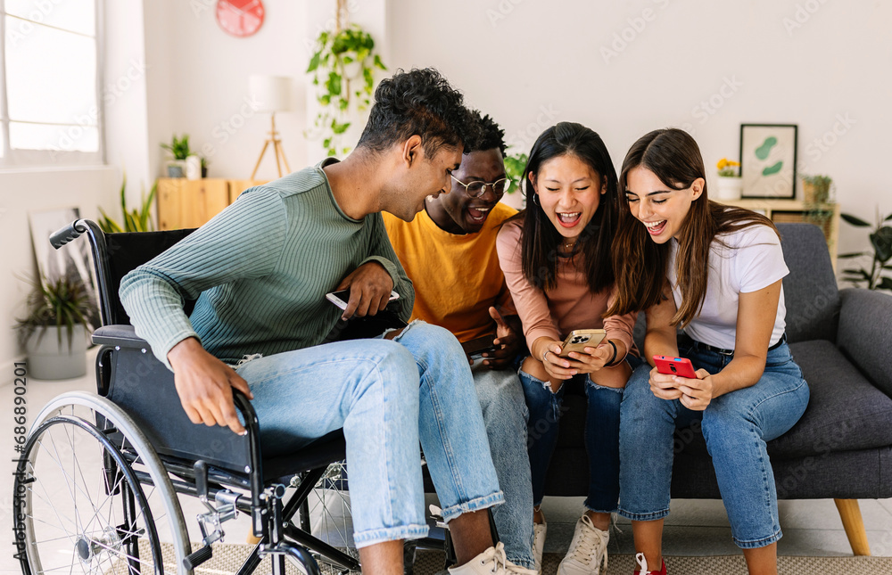 Diverse group of young friends laughing using mobile phone together at ...