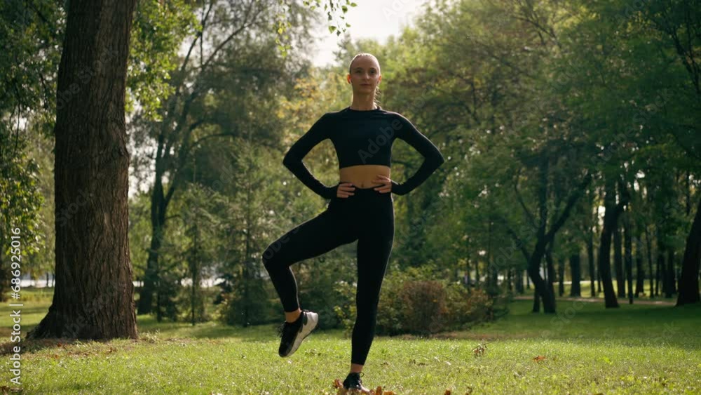 A sports girl during morning workout in the fresh air makes circular ...