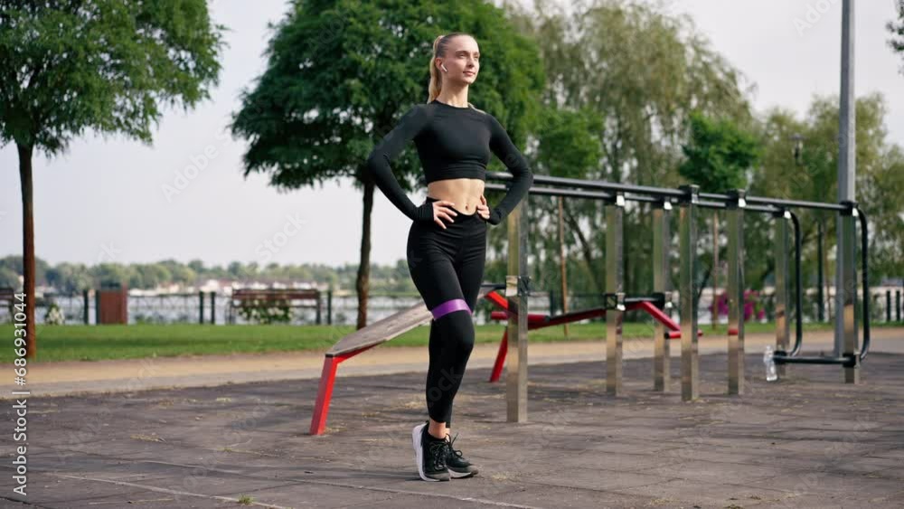 Beautiful girl in sports uniform performs exercises to pump up her legs ...