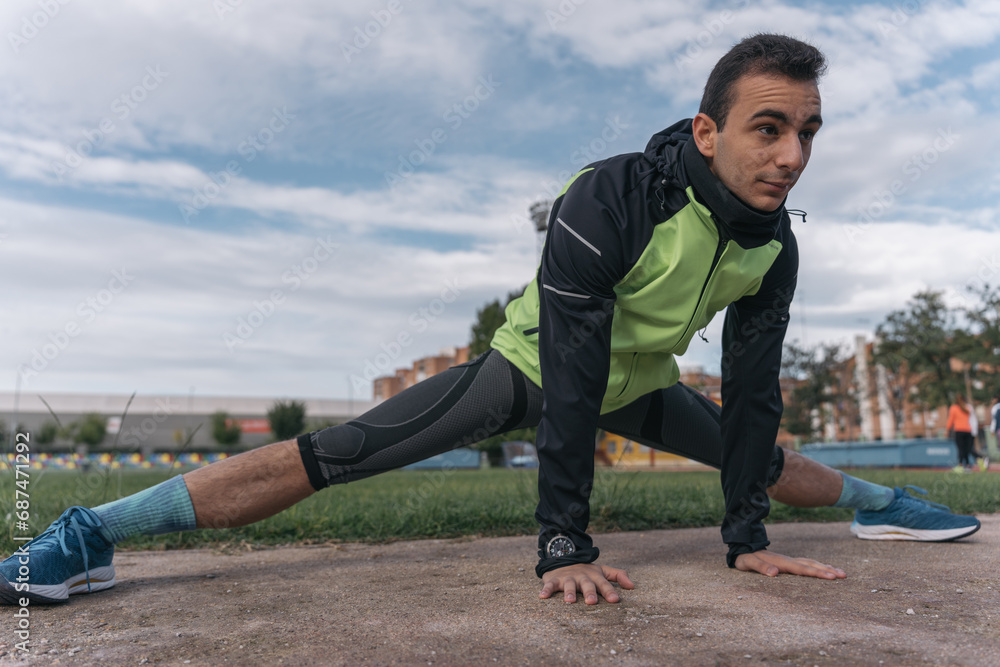 Young athlete warming up his legs on the athletics track. Male athlete ...