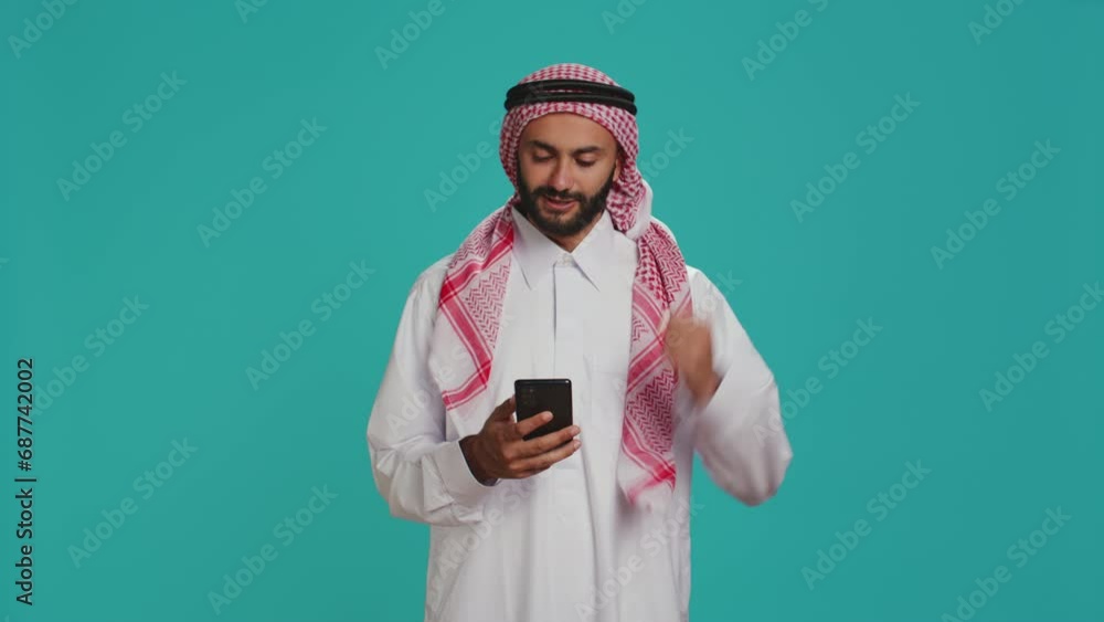 Muslim person in traditional costume having smartphone in hands and ...