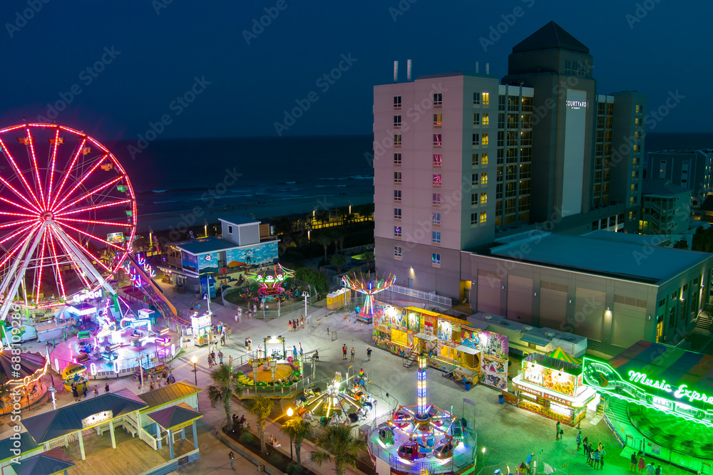 aerial shot of the Carolina Beach Boardwalk with ocean water, people on ...