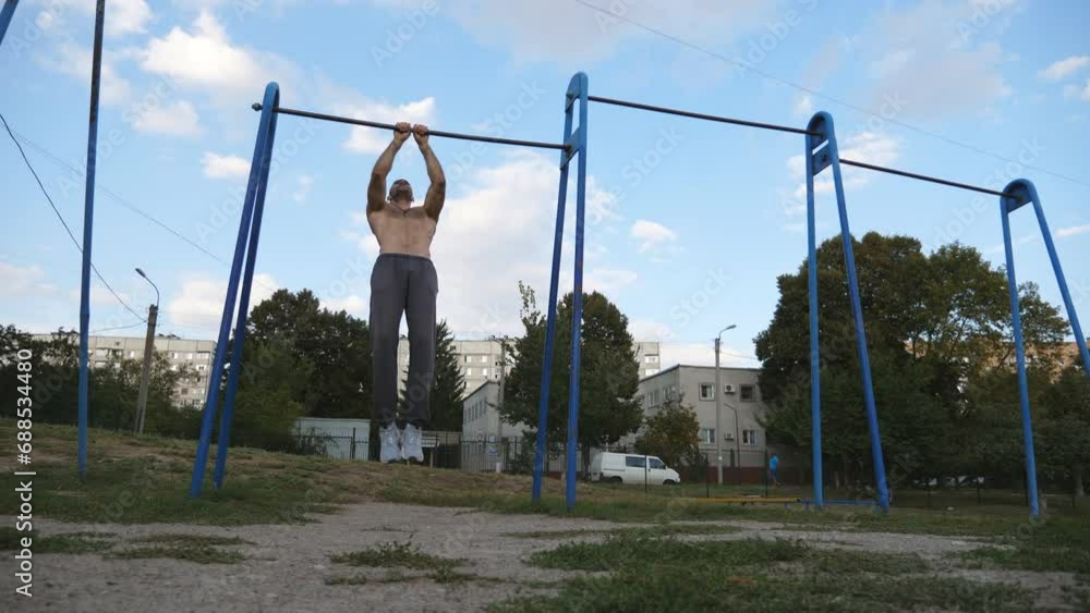 Muscular athlete doing pull ups at sports ground. Young sportsman ...
