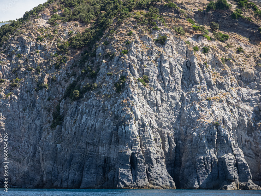 Weathered seaside rock face texture with parts of green and blue water ...