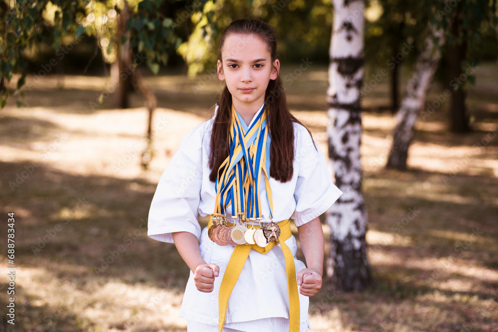 Young girl wearing karate fighter uniform and medals holding trophy ...