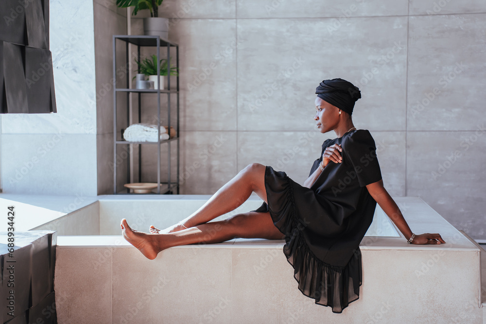 Lonely African girl in traditional clothes and black turban sitting on ...