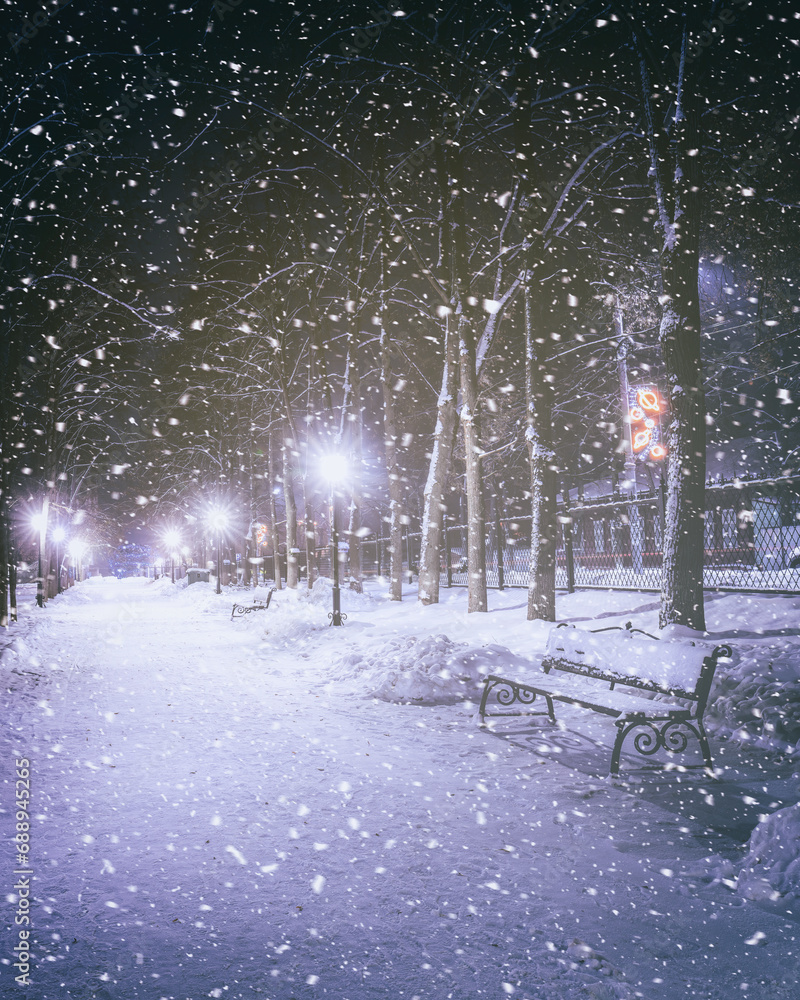 Snowfall in a winter park at night with glowing lanterns, pavement ...