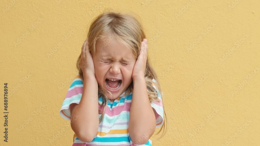 Unhappy sad angry little child girl close eyes and cover ears by hands ...