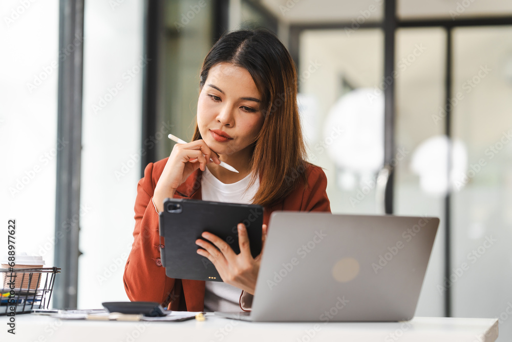 Middle-age attractive Asian insurance agent is focused on her laptop ...