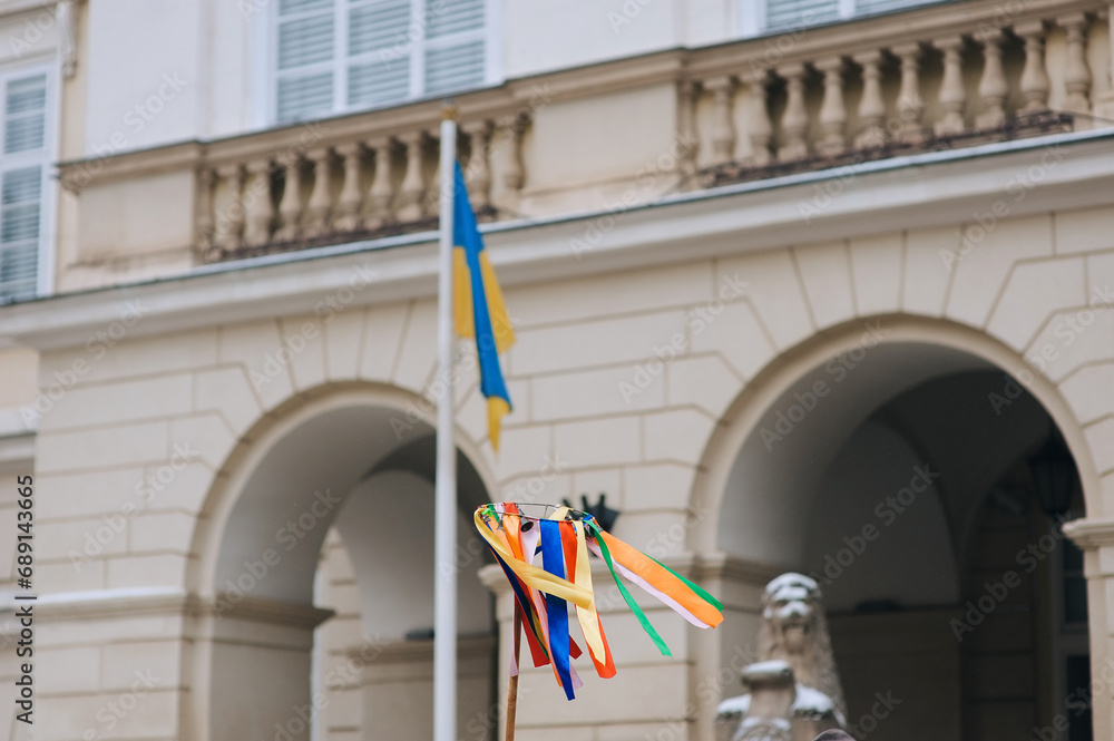 Handmade stick with multi-colored ribbons on the background of houses ...