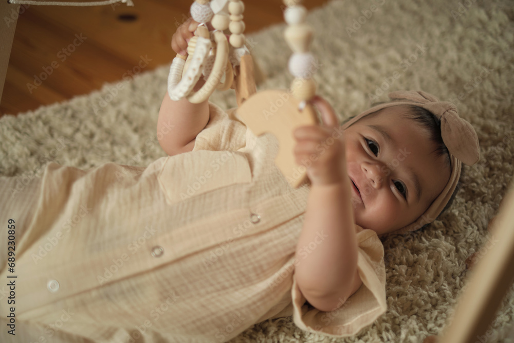 Engrossed in play, a baby reaches for wooden rings, supported by a ...