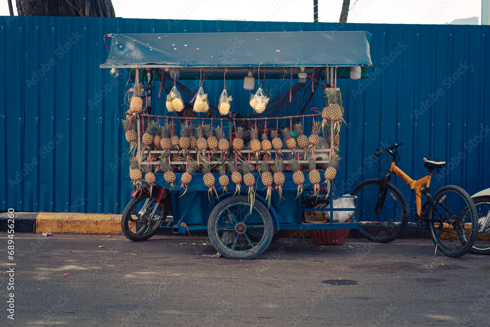 Food cart selling fresh pineapples in the side of the road showing the ...