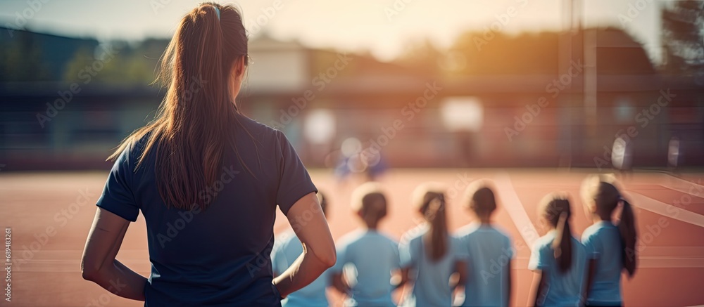 Female PE teacher instructing children in school gym from behind Stock ...
