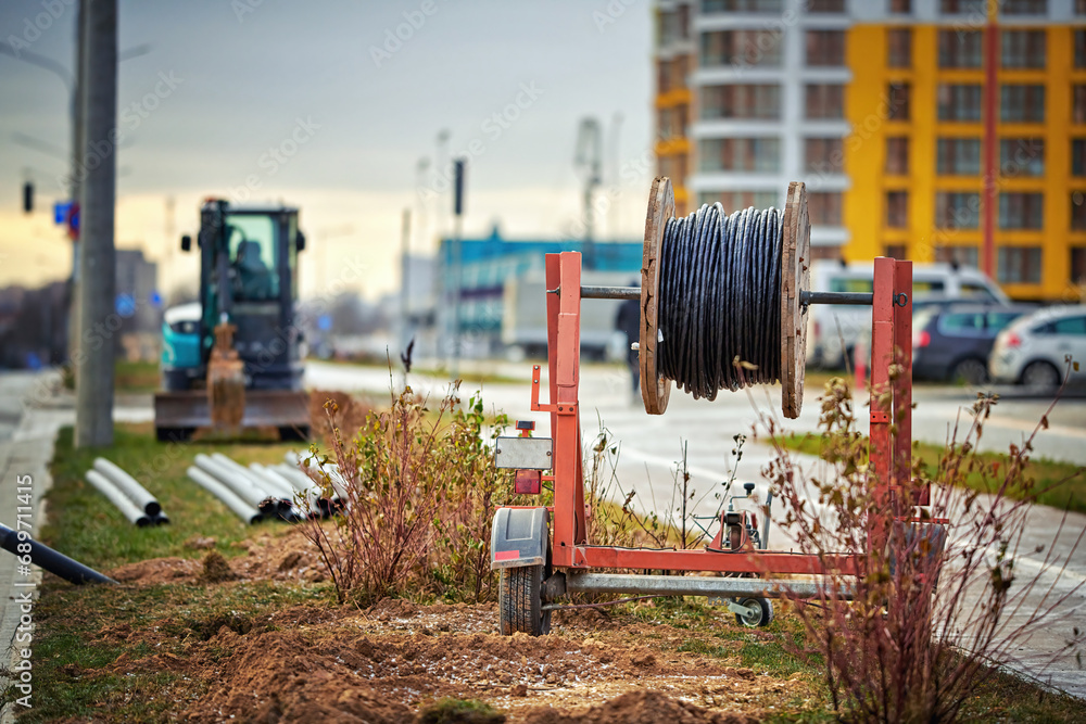 Wooden drum with fiber optic cable mounted on trailer, excavator ...
