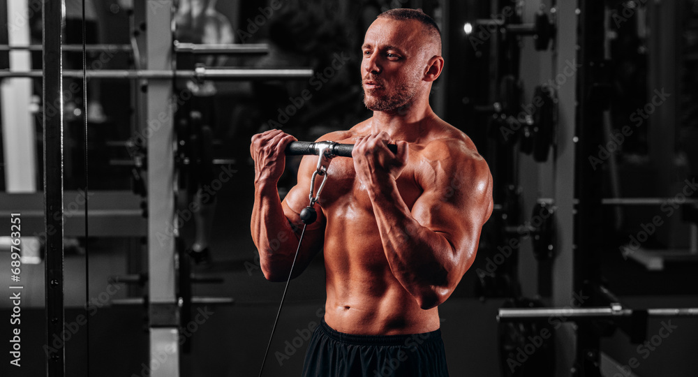Muscular bodybuilder doing bicep curls in cable crossover gym machine ...