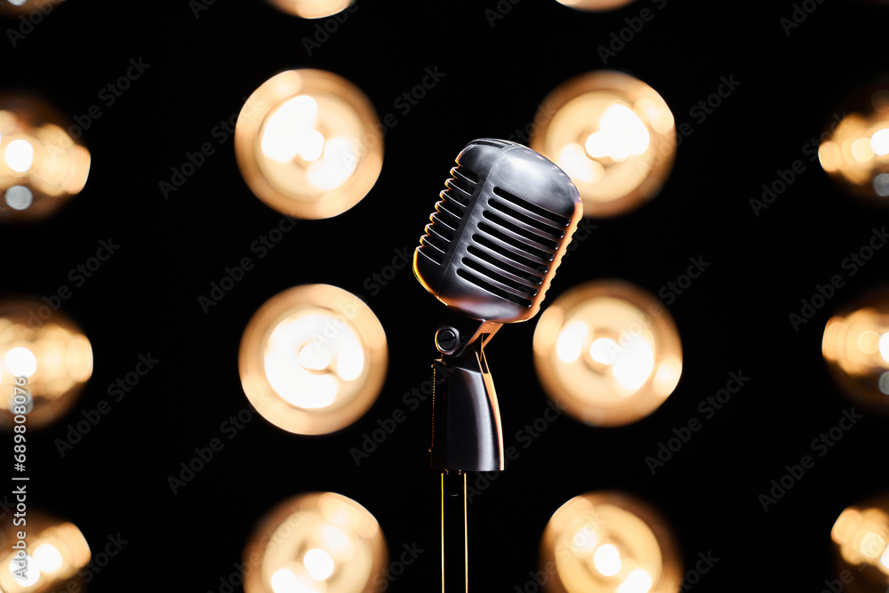 One retro microphone on empty stage with bulb lights on backdrop. Close ...