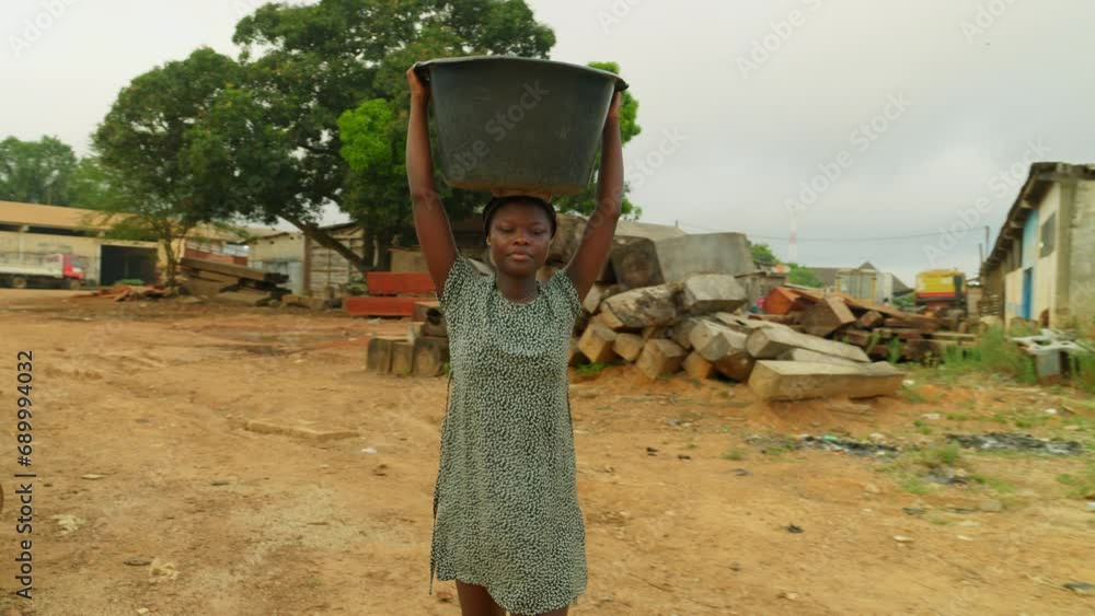 Walking while carrying a water filled basin on top of her, a local ...