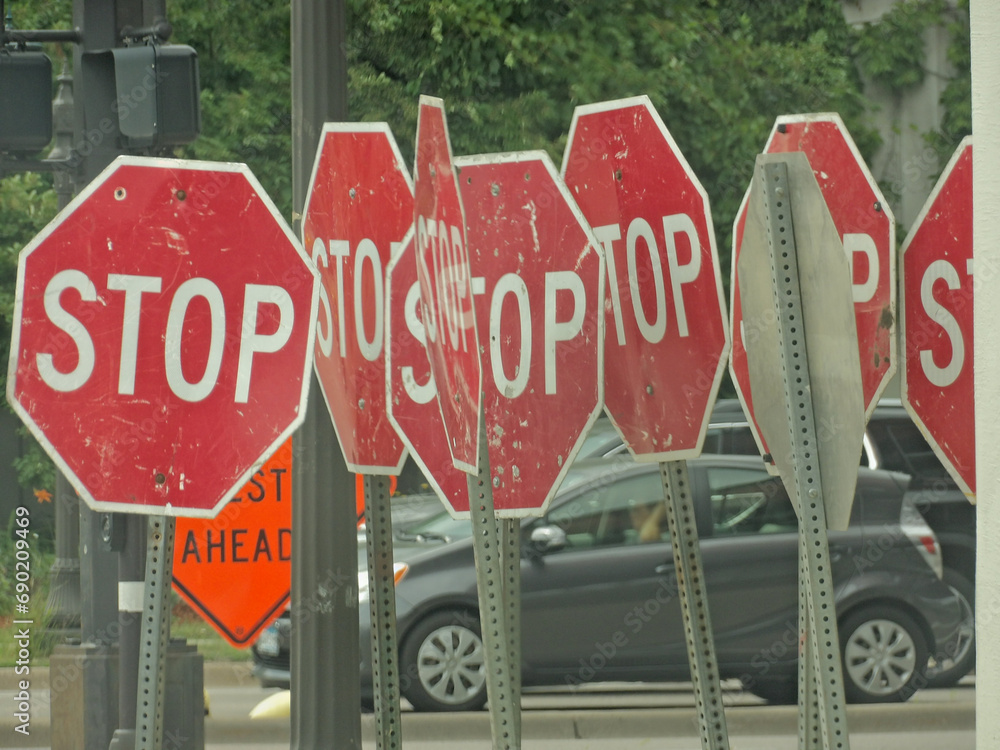 Variety of red stop signs and road signs are positioned near a street ...