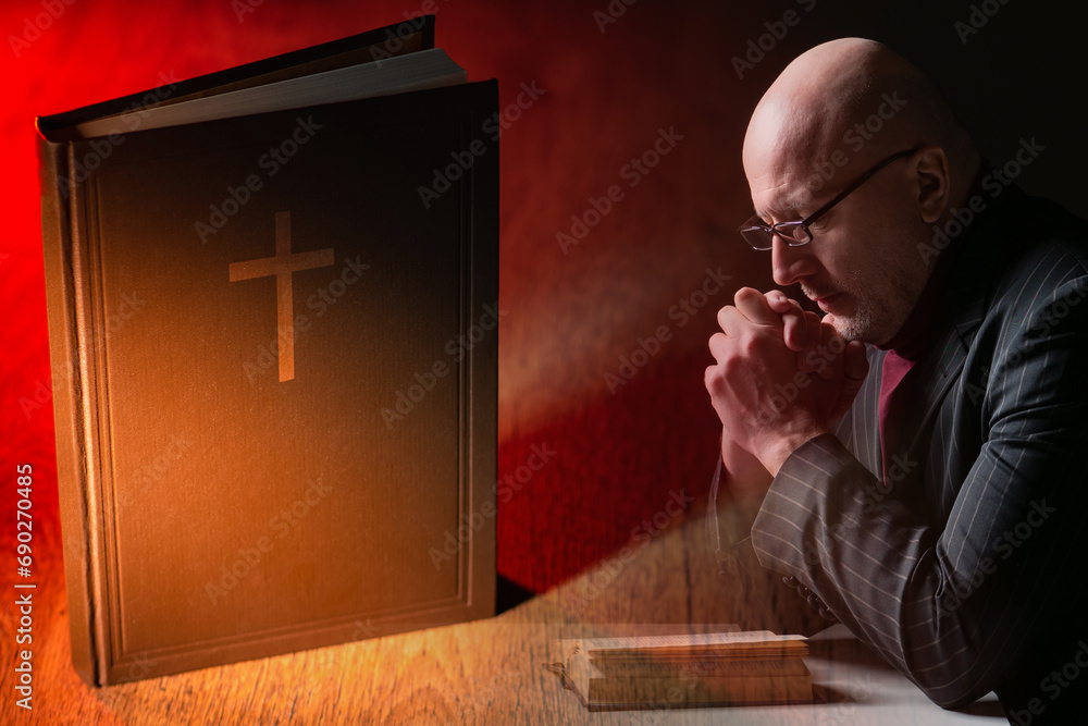 Christian prayer. Man praying before bible. Guy crossed his palms for ...