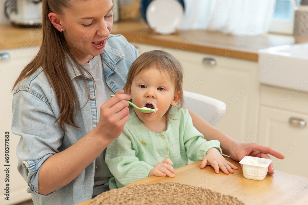 Happy family at home. Mother feeding her baby girl from spoon in ...