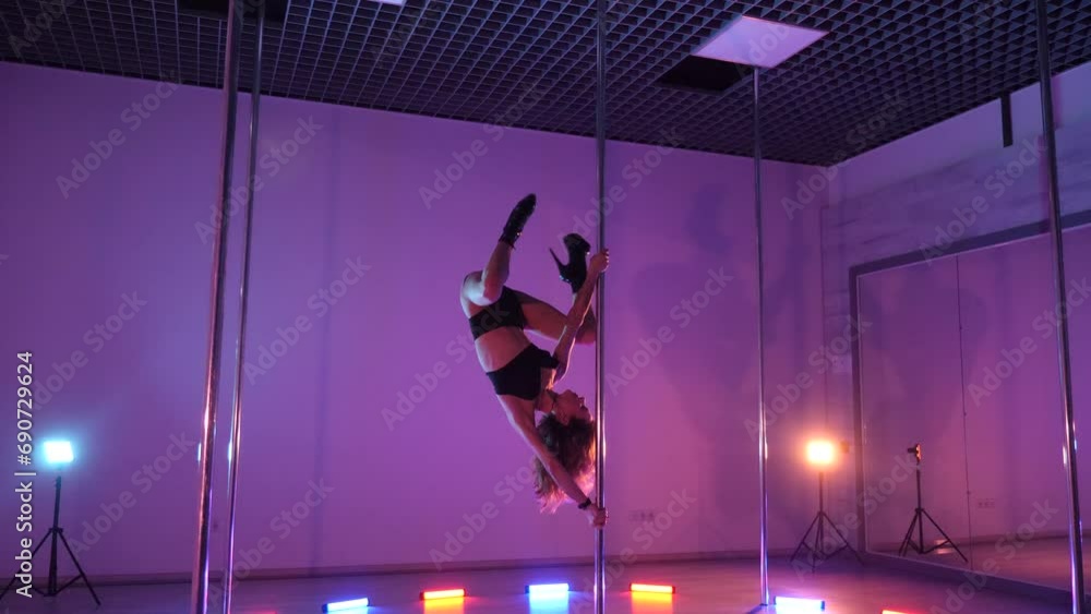 Sexy woman dances a pole dance in a disco club. Erotic dance on a pole. Exotic pole dance ...