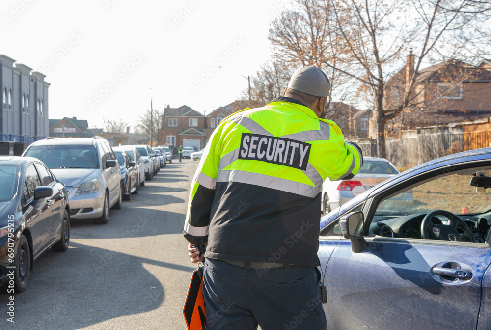 Security guard conducting access control, traffic control, and parking ...