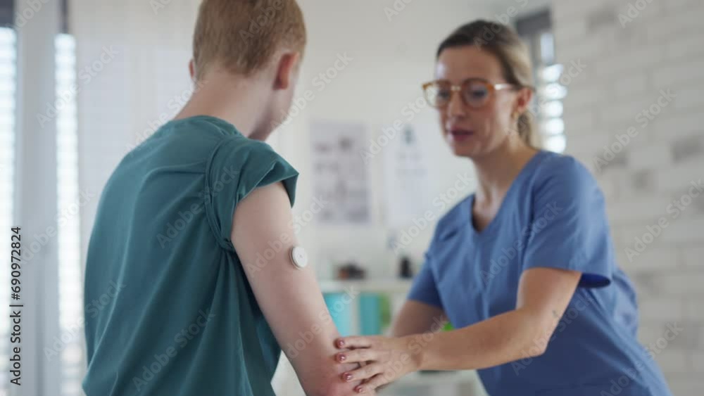 Nurse applying a continuous glucose monitor sensor on arm of a diabetic ...