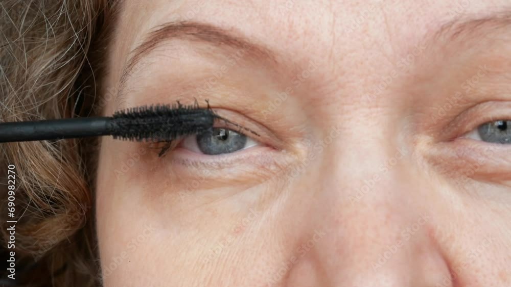 middle aged female's eye with drooping eyelid making eyebrow makeup ...