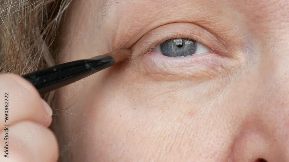 middle aged female's eye with drooping eyelid making eyebrow makeup ...