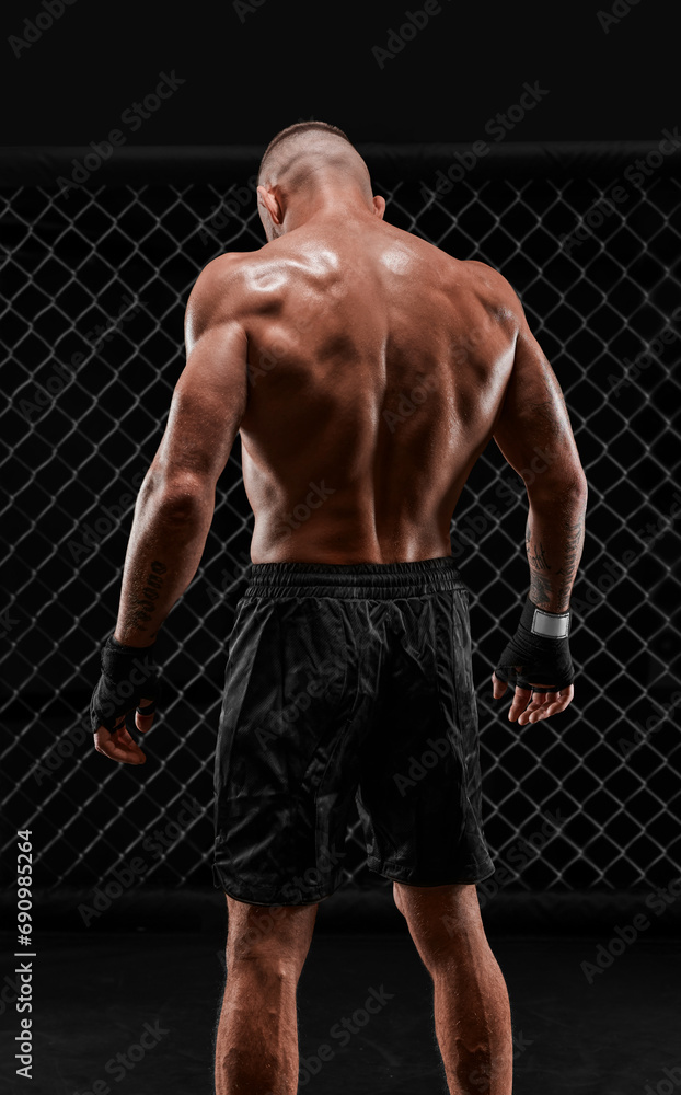 Conceptual image of a kickboxer. A real fighter stands in the real cage ...